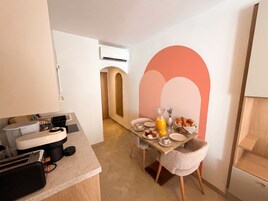 Cozinha moderna com área de refeições, incluindo um espaço para café da manhã com croissants, suco de laranja e um vaso de lavanda.