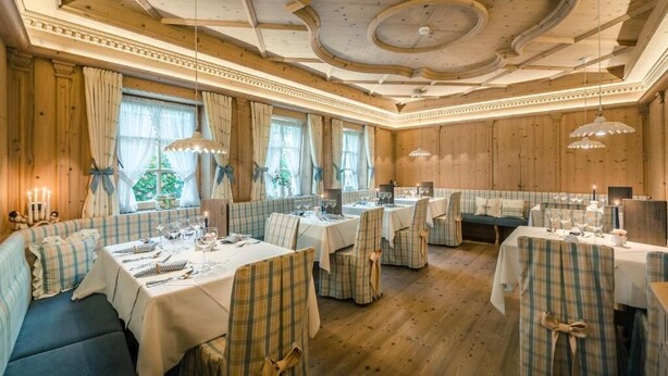 Um restaurante com paredes e teto de madeira, toalhas de mesa xadrez e ambiente acolhedor.