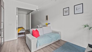 Uma sala de estar moderna com um sofá, uma mesa pequena com um vaso e um quadro na parede.