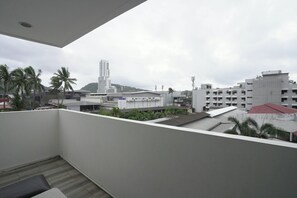 Uma varanda com vista para a paisagem urbana, incluindo edifícios e palmeiras.