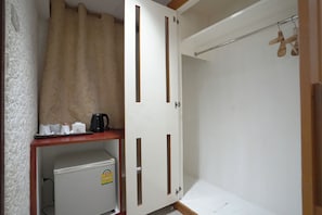 Casa de banho com chuveiro, sanita e pequeno armário com artigos de higiene.