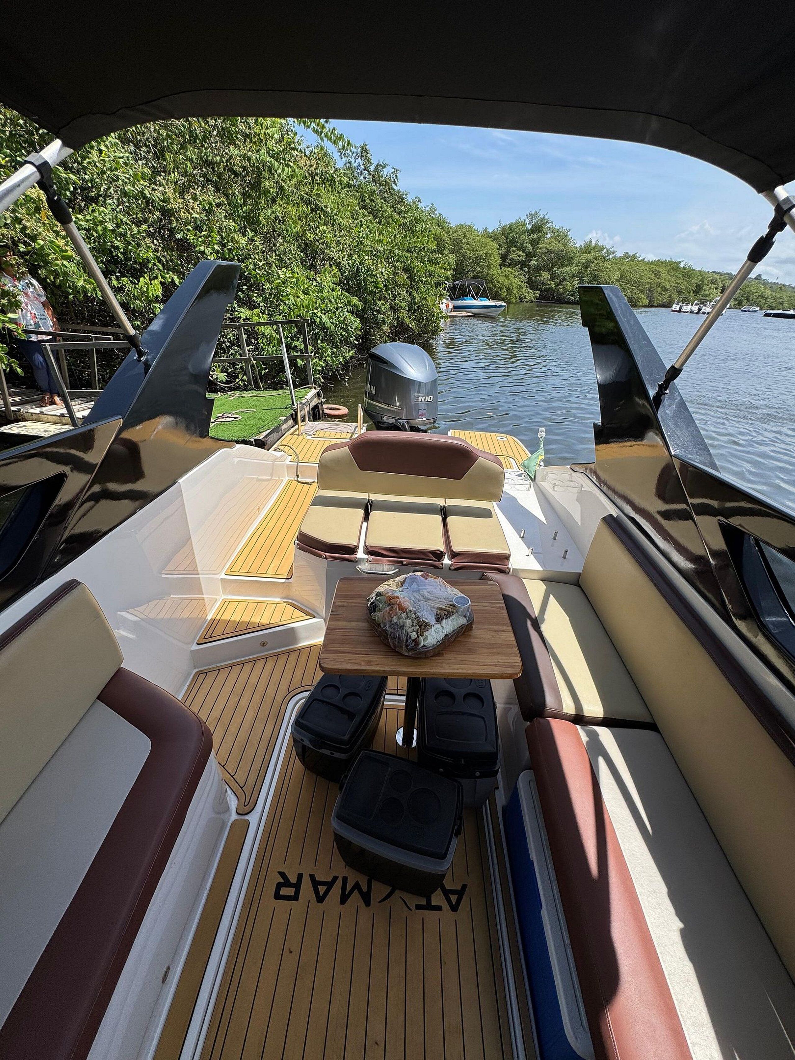 Convés de barco com assentos, uma mesa e um motor.