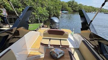 Convés de barco com assentos, uma mesa e um motor.