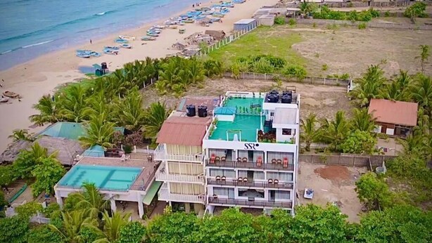 Um hotel com piscina, acesso à praia e vista para o oceano.