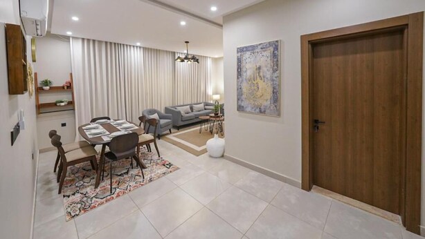Uma sala de estar moderna com área de jantar, sofá, mesa de centro e uma grande porta de madeira.