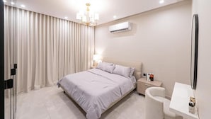 Quarto moderno com cama, mesa de cabeceira, luminária, aparelho de ar condicionado e espelho.