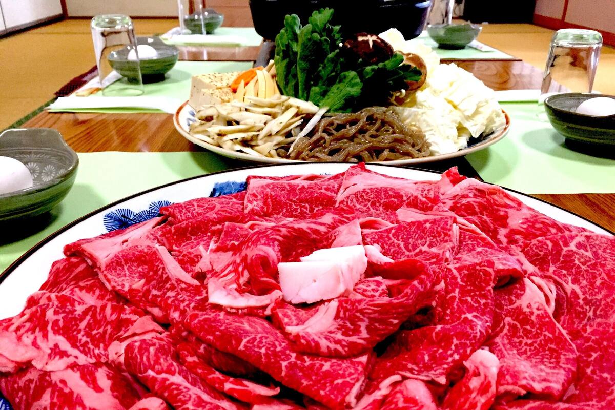 Uma mesa com diversos alimentos, incluindo carne fatiada, vegetais e uma tigela de sopa.