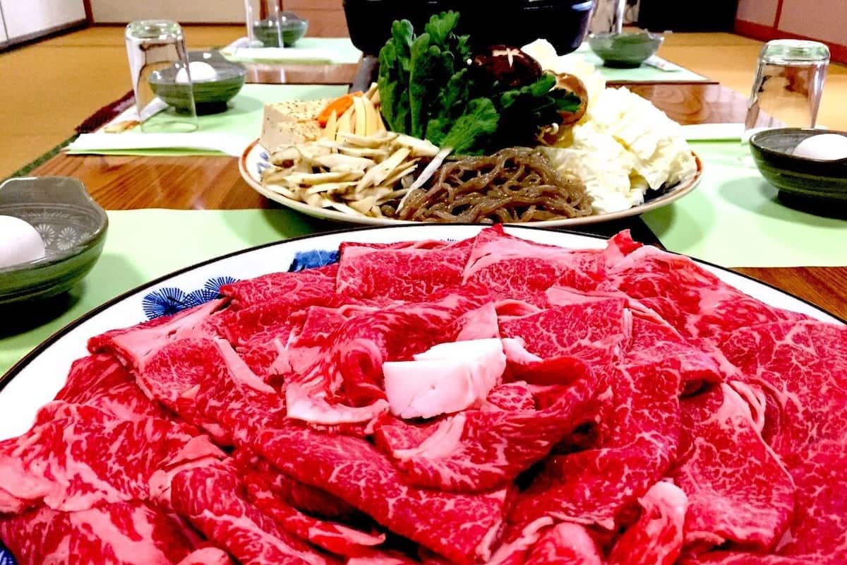 Mesa de jantar com diversos pratos, incluindo carne fatiada e legumes.