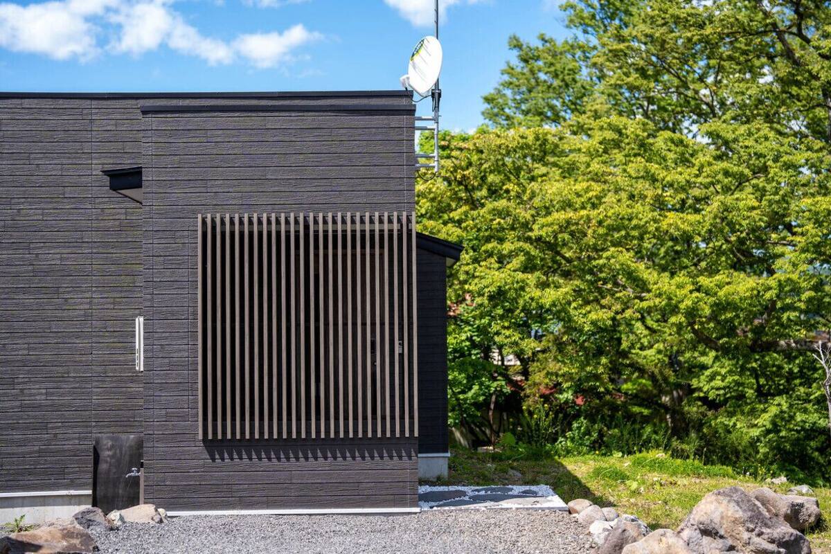 Um edifício moderno com fachada escura, janela vertical e antena parabólica.