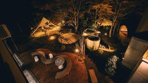 Um jardim no terraço com uma tenda, áreas de estar e um barril.