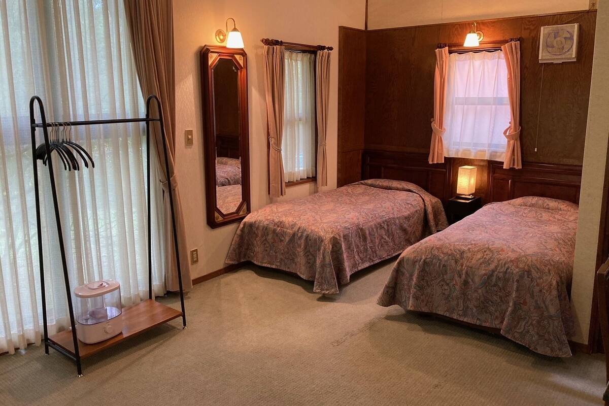 Quarto com duas camas, um espelho, aquecedor e um varal.