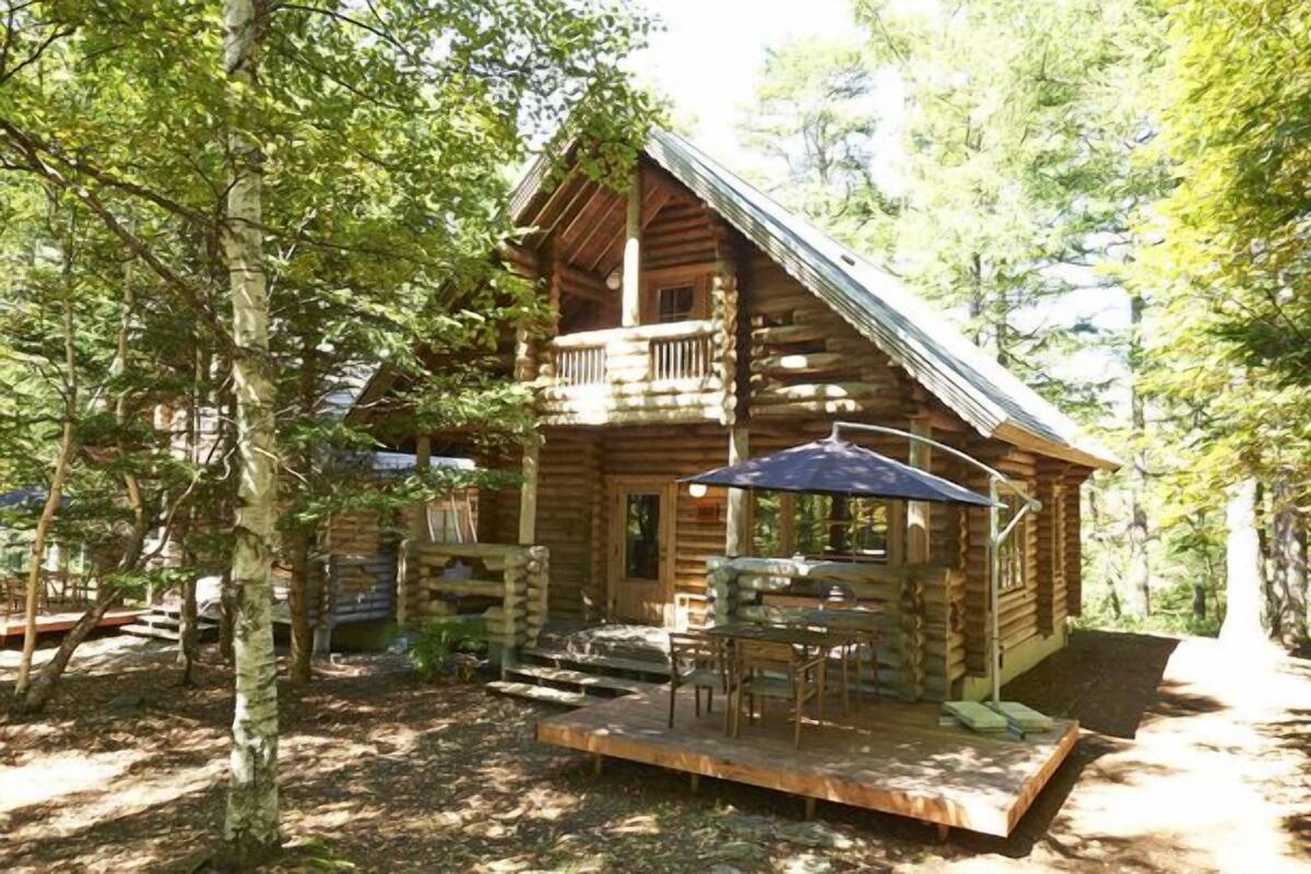 Uma cabana de tronco com varanda, área de estar externa e um deck de madeira.