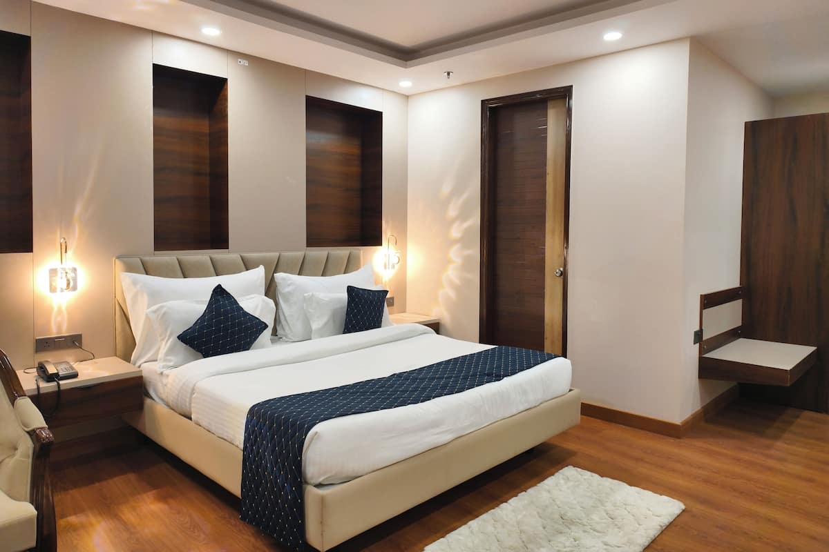 Quarto moderno com uma cama grande, abajures, um guarda-roupa de madeira e uma cadeira de madeira pequena.