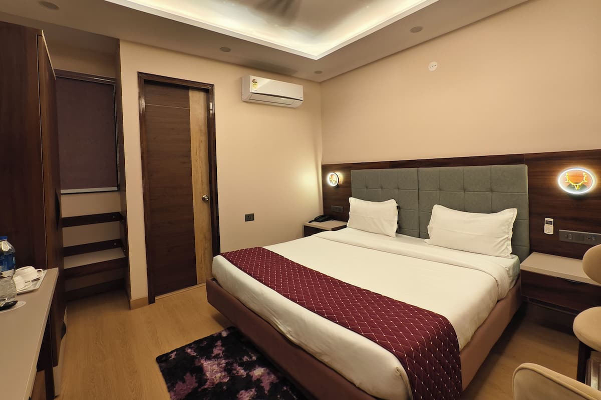 Quarto de hotel com cama, mesa de cabeceira e ventilador de teto.