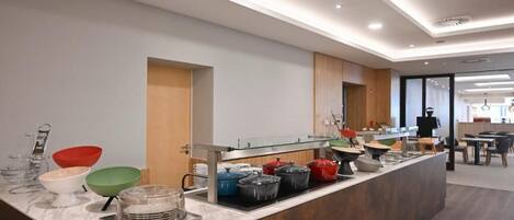 Uma cozinha moderna com bancada de mármore, utensílios diversos e uma vitrine de vidro.
