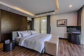 Quarto moderno com cama grande, televisão e parede de destaque em madeira.