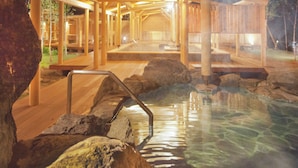 Uma área de spa em madeira com uma nascente termal, degraus de madeira e um corrimão de metal.