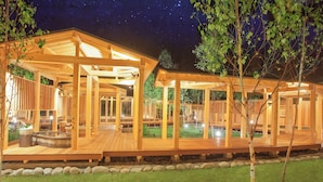 Uma cabana de madeira com varanda, hidromassagem e céu noturno limpo.