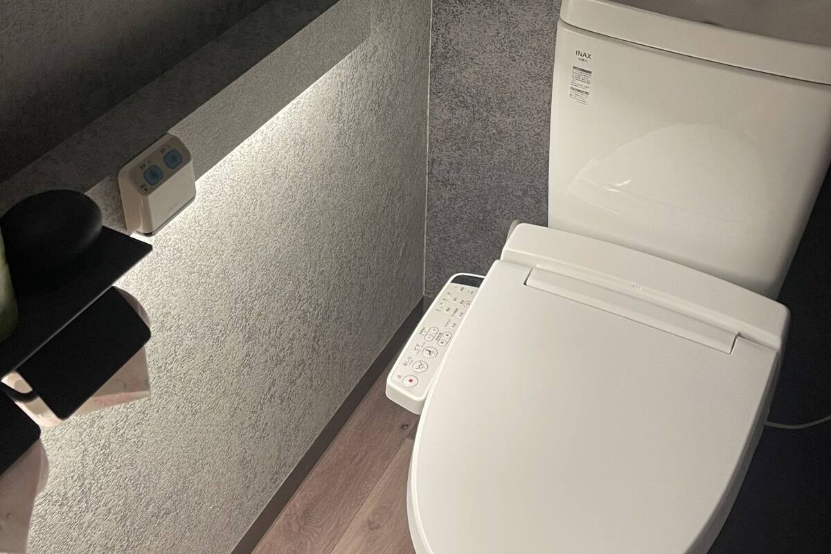 Casa de banho moderna com sanita, painel de controlo e dispositivo fixado na parede.