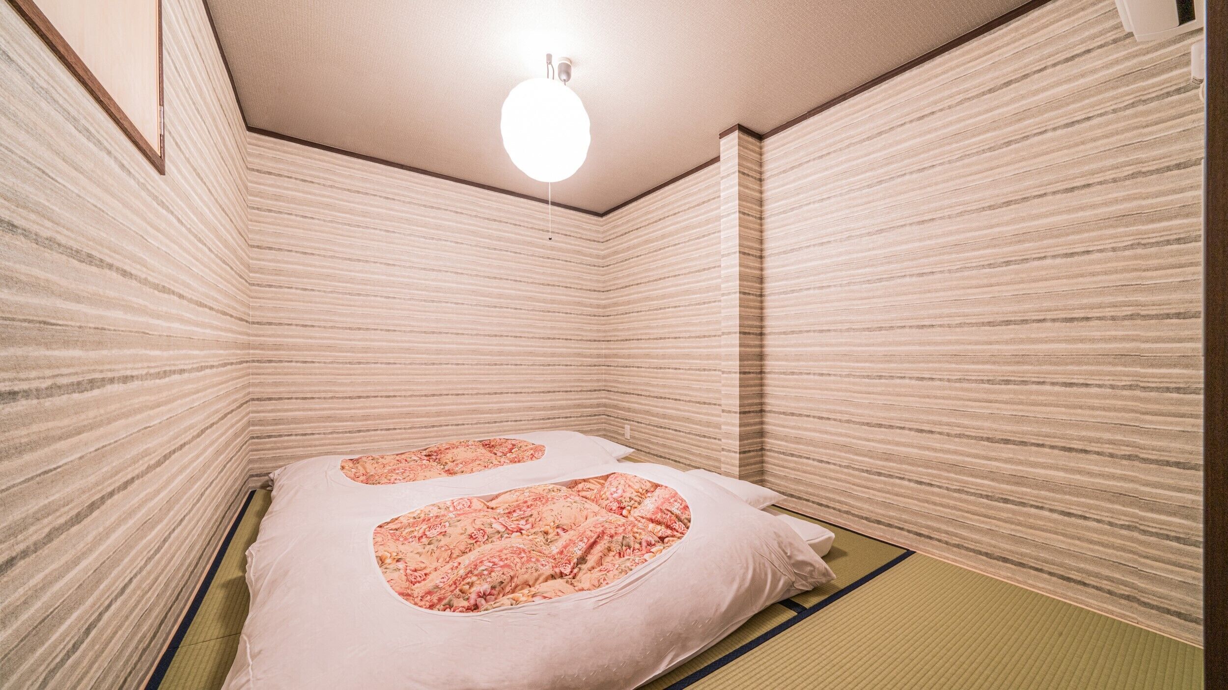 Quarto com cama, luminária no teto e paredes de madeira.