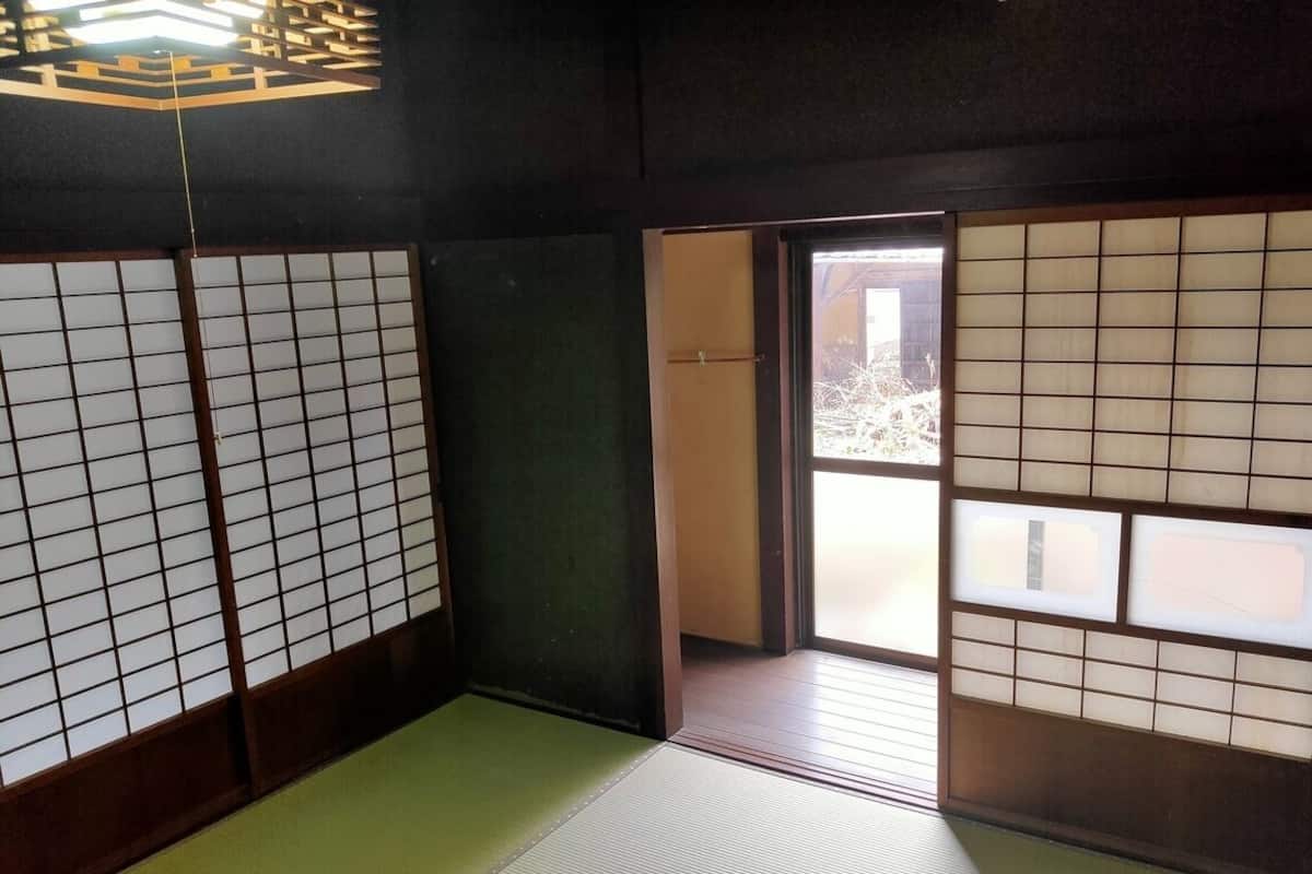Um quarto japonês tradicional com piso de tatame, painéis shoji e uma porta deslizante que dá para uma varanda.