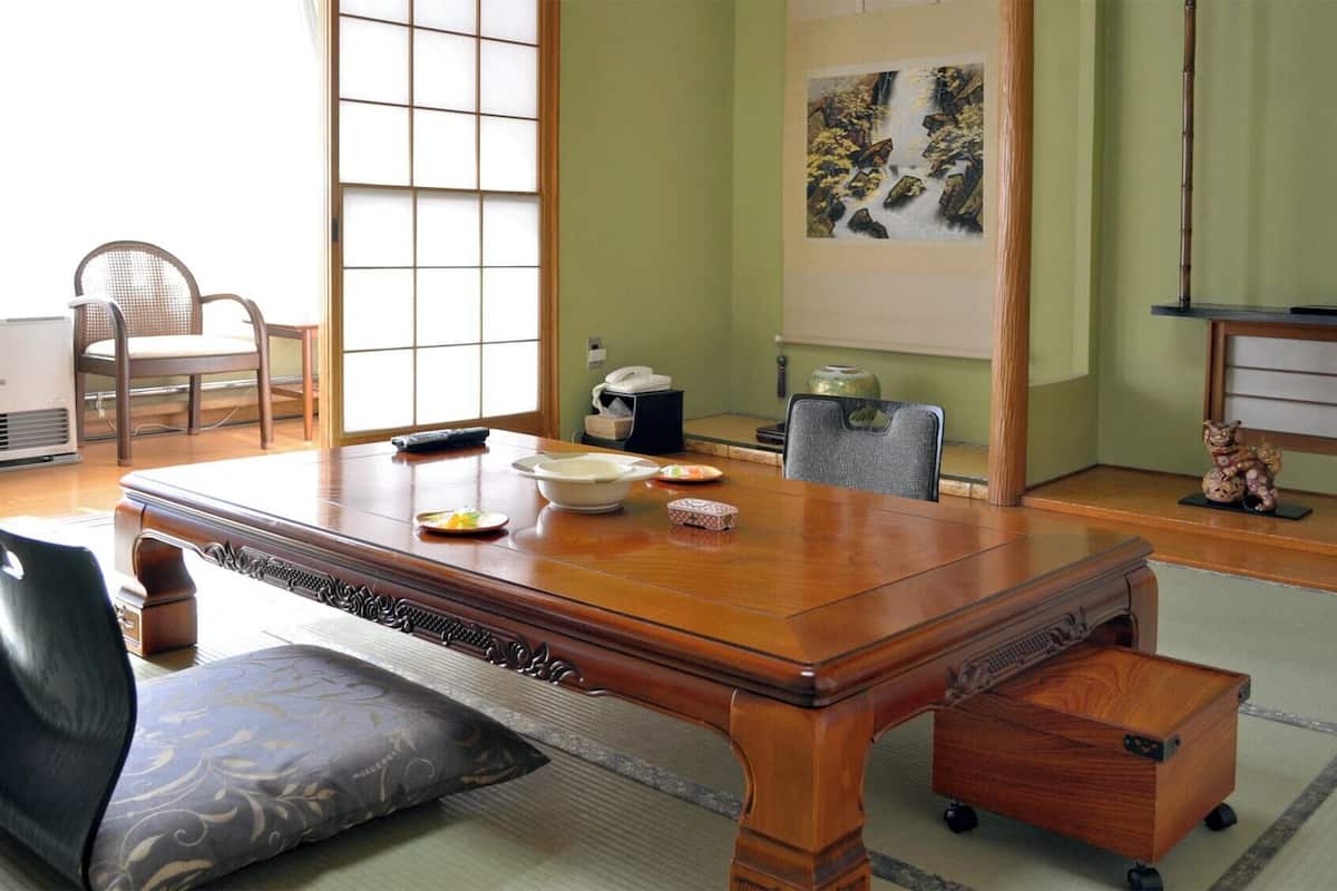 Um quarto tradicional japonês com piso de tatame, uma mesa de madeira baixa e uma porta de papel shoji.