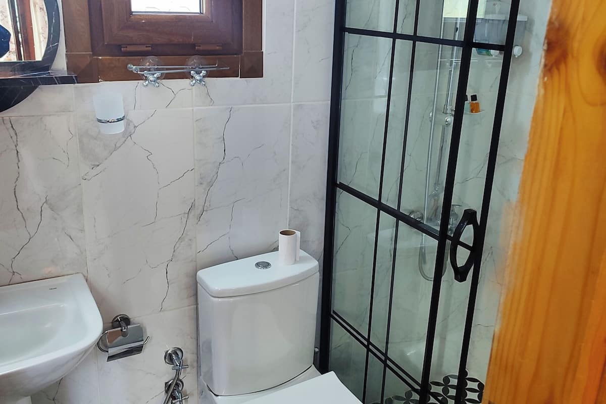 Casa de banho com sanita, bidé e lavatório, tudo em azulejos de mármore.