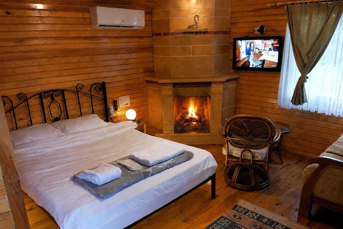 Um quarto aconchegante com cama, lareira, televisão e janela com cortinas.