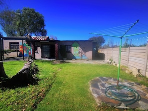 Uma casa com um mural colorido, um caminho de pedra e uma mangueira verde.
