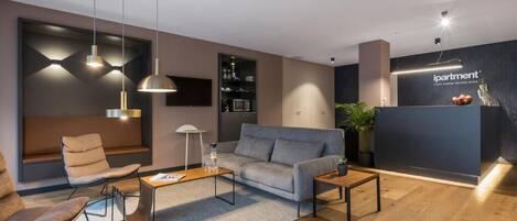 Uma sala de estar moderna com sofá, poltronas, mesa de centro, luminárias pendentes, um balcão de recepção e um vaso de plantas.