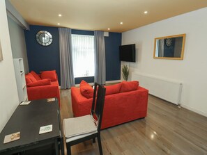 Uma sala de estar moderna com um sofá, uma mesa de jantar, uma televisão e um relógio na parede.