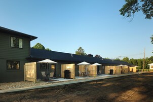 Uma fileira de cabanas com área de estar ao ar livre e churrasqueira.
