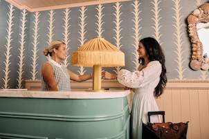 Uma área de recepção com balcão, luminária e espelho na parede.