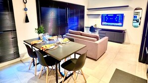Uma sala de estar moderna com área de jantar, sofá, TV e cozinha.