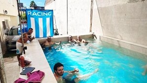 Piscina com pessoas, um carro e uma faixa azul e branca com a palavra 'RACING'.