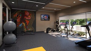 Academia com equipamentos de ginástica, uma grande janela e um mural colorido.