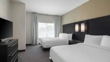 Quarto de hotel com duas camas, televisão de tela plana, cômoda e uma janela grande com cortinas.