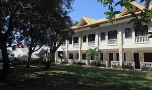 Um edifício com vários andares, varandas, telhado telhado e um gramado bem cuidado.