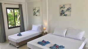 Quarto de hotel com duas camas, uma janela com cortinas, uma mesinha de cabeceira com abajur e obras de arte na parede.