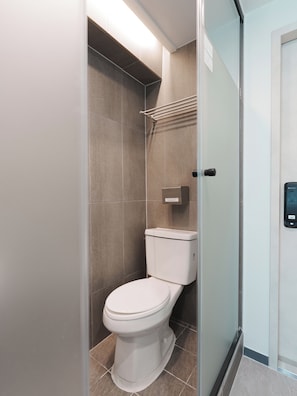 Uma casa de banho moderna com sanita, cabine de duche em vidro e suporte para toalhas.