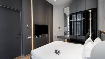 Quarto de hotel moderno com uma cama grande, televisão de tela plana, espelho e armário.