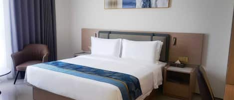 Quarto de hotel com uma cama grande, uma mesa de cabeceira, uma cadeira e um quadro na parede.