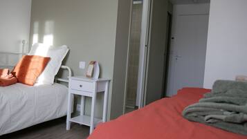 Quarto de hotel com cama, mesa de cabeceira, espelho e porta.