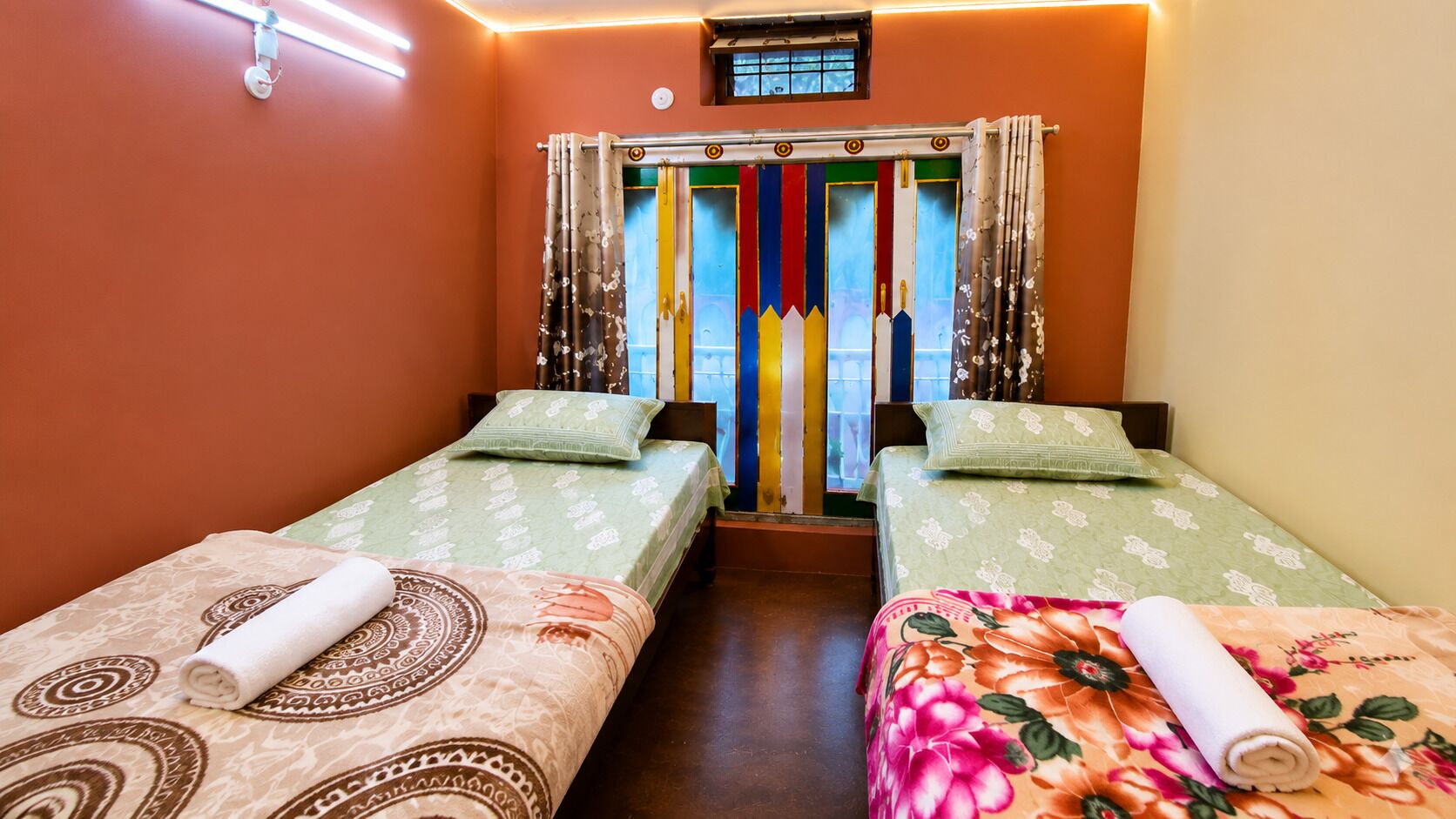 Quarto com duas camas, cada uma com colcha estampada e toalha enrolada.