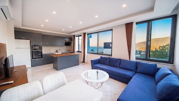Uma sala de estar moderna com um sofá azul, uma mesa de centro branca e uma TV sobre um suporte de madeira.