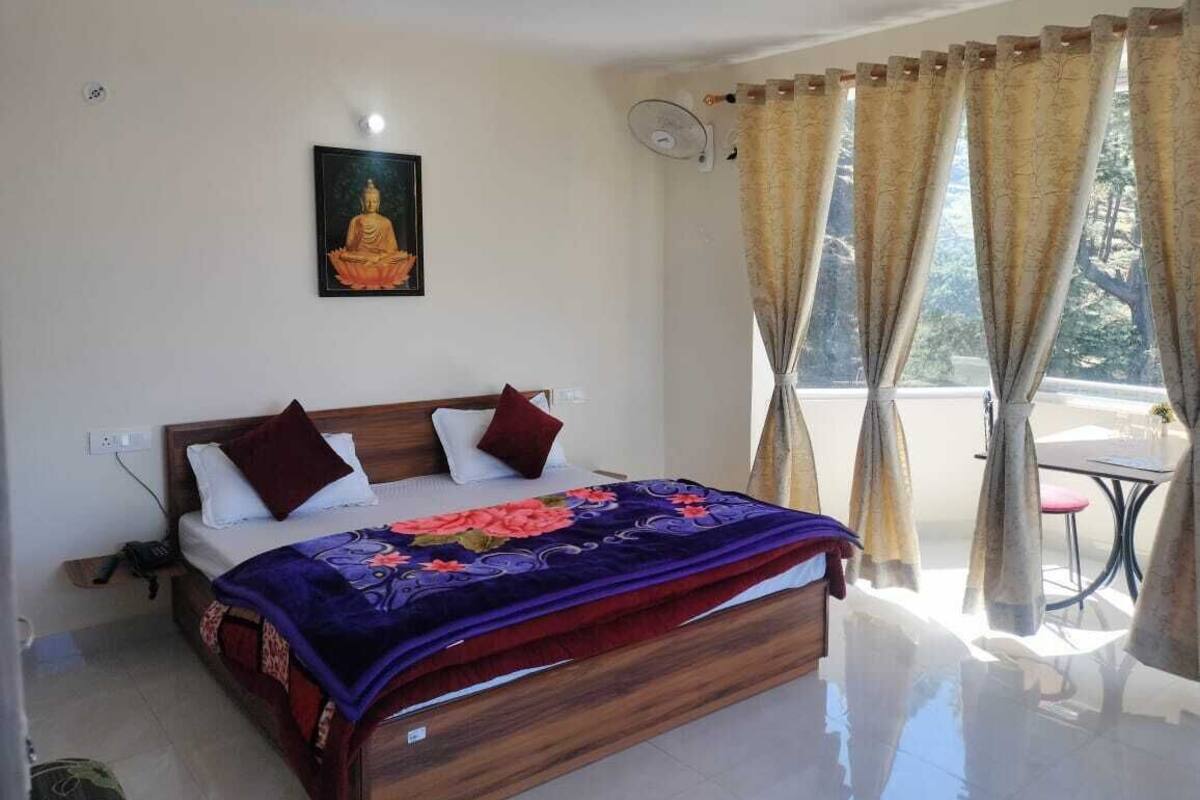 Quarto com uma cama, um quadro na parede, cortinas e vista para o exterior.