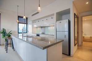Uma cozinha moderna com bancadas de granito, eletrodomésticos de aço inoxidável e iluminação pendente.