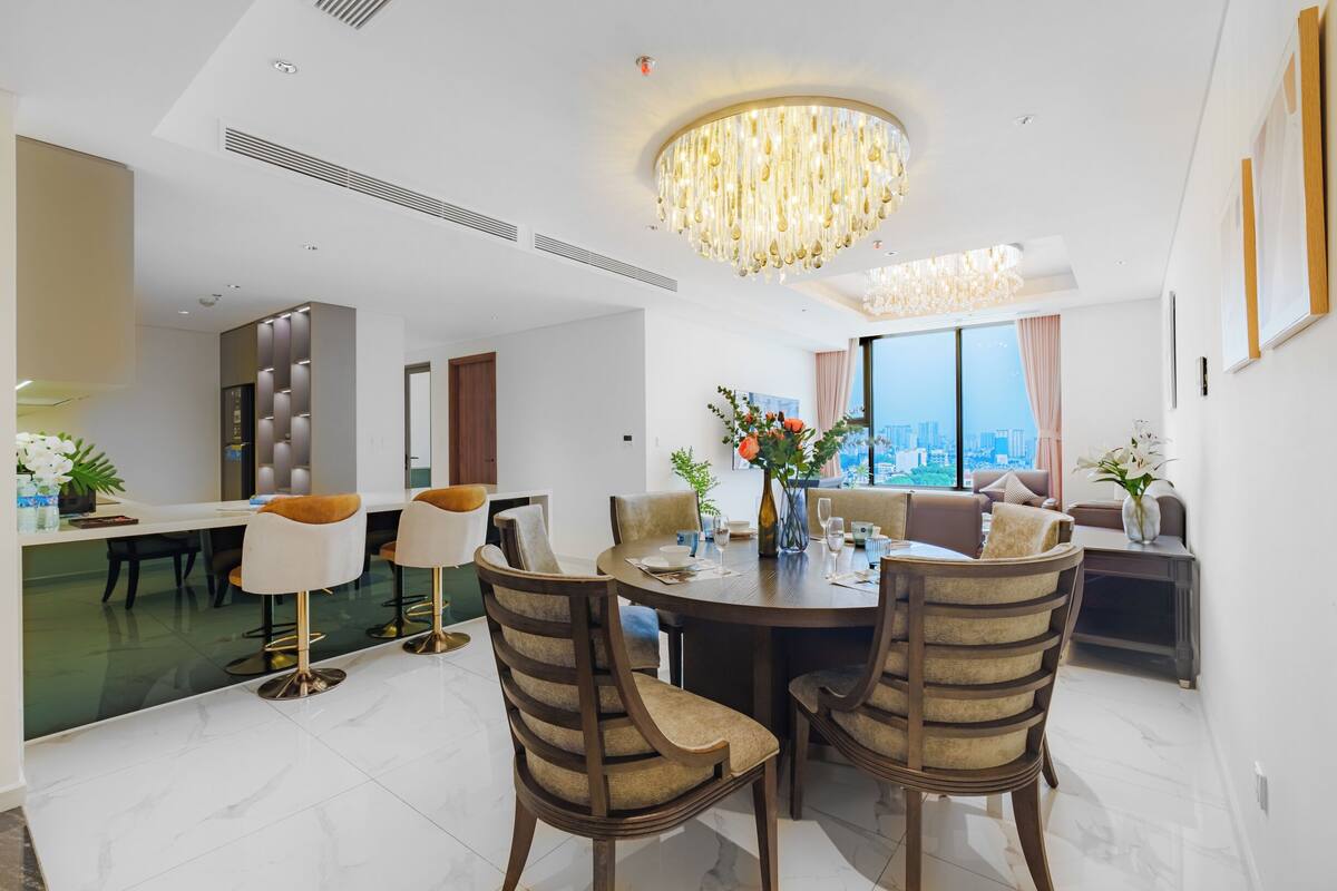 Uma sala de jantar moderna com um candelabro, mesa redonda e banquetas de bar.