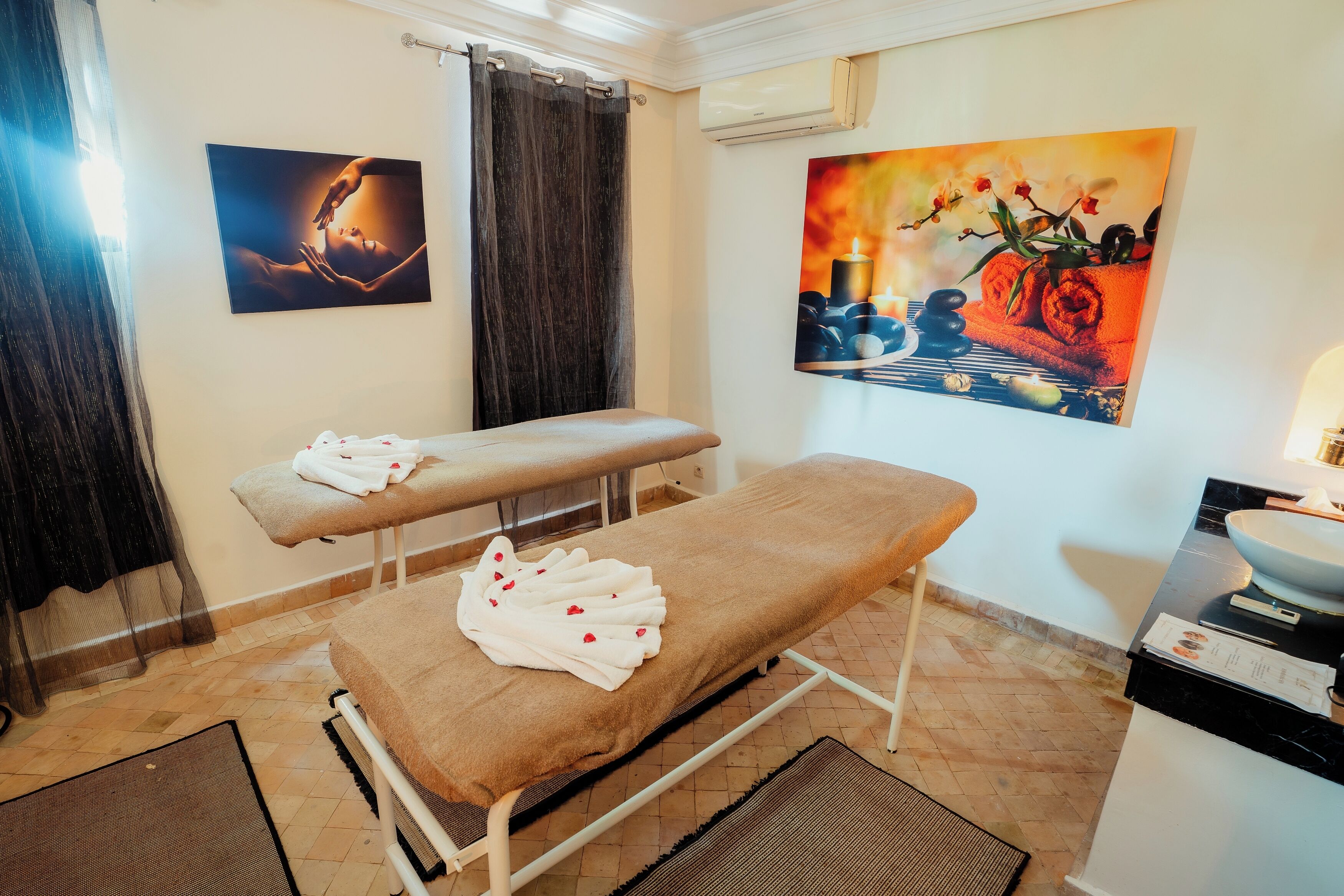 Sala de spa com mesa de massagem, toalhas, um quadro e uma pia.