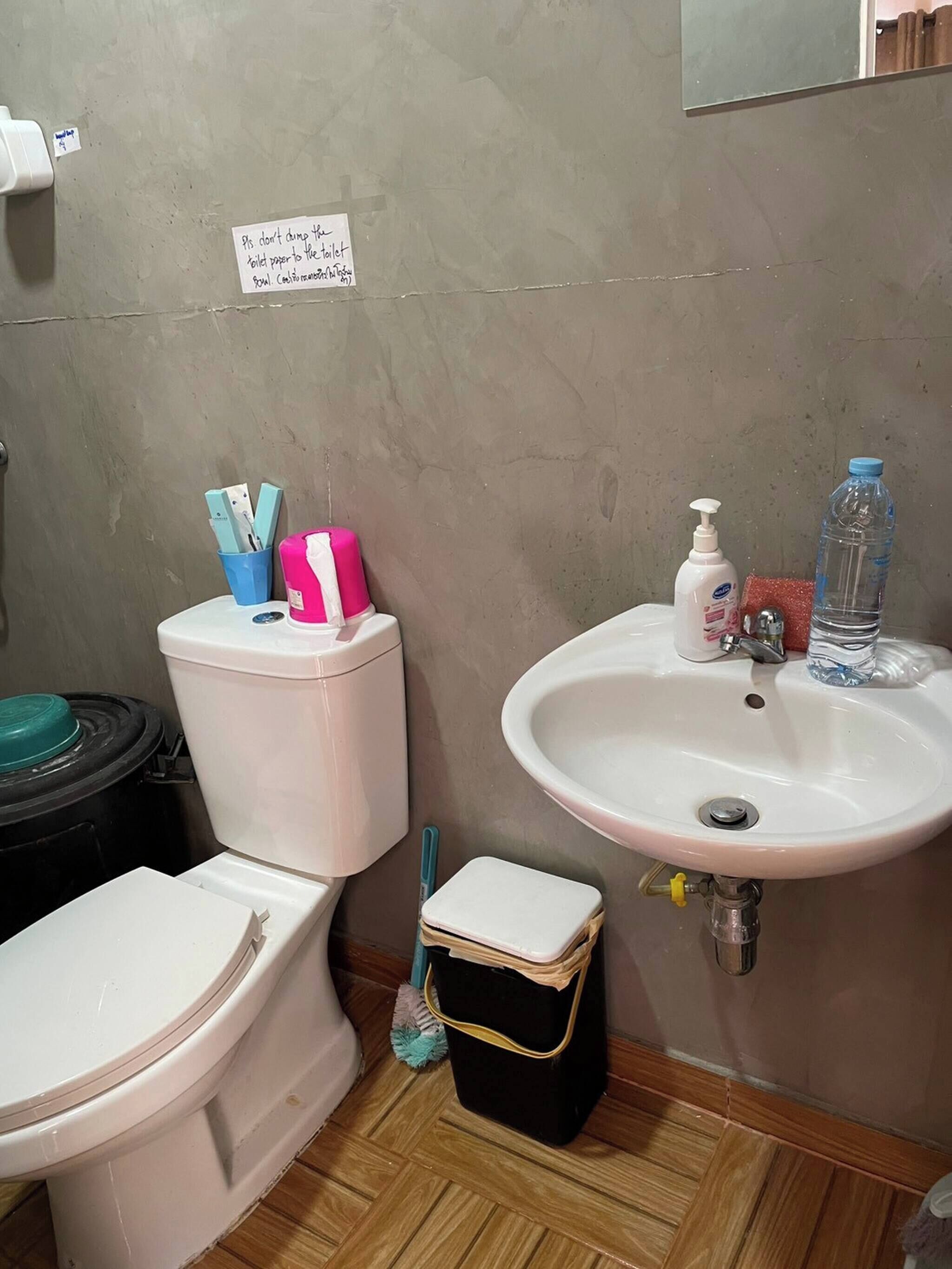 Casa de banho com sanita, lavatório e um caixote do lixo.